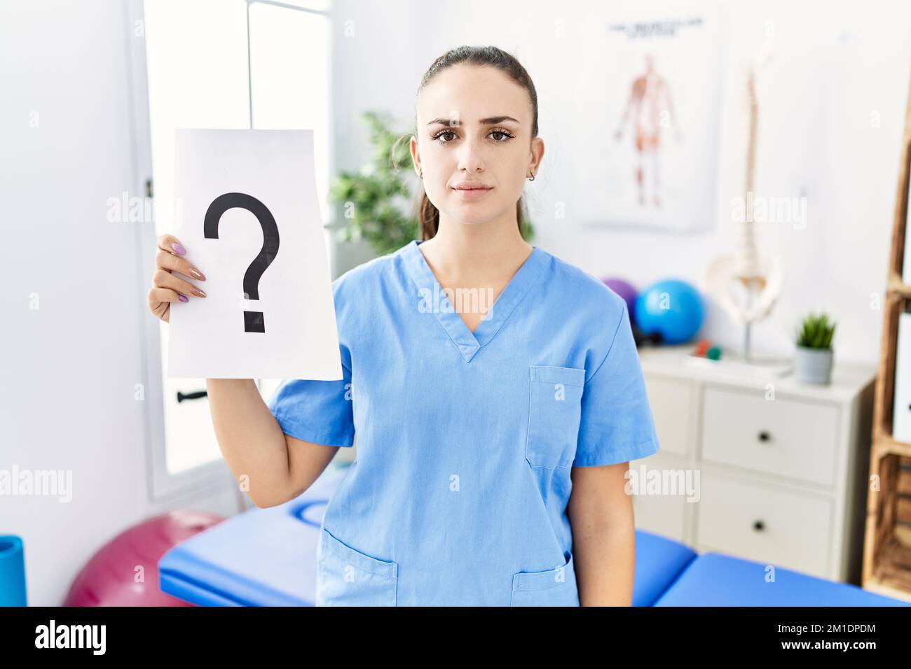 Young physiotherapist woman holding question mark thinking attitude and ...