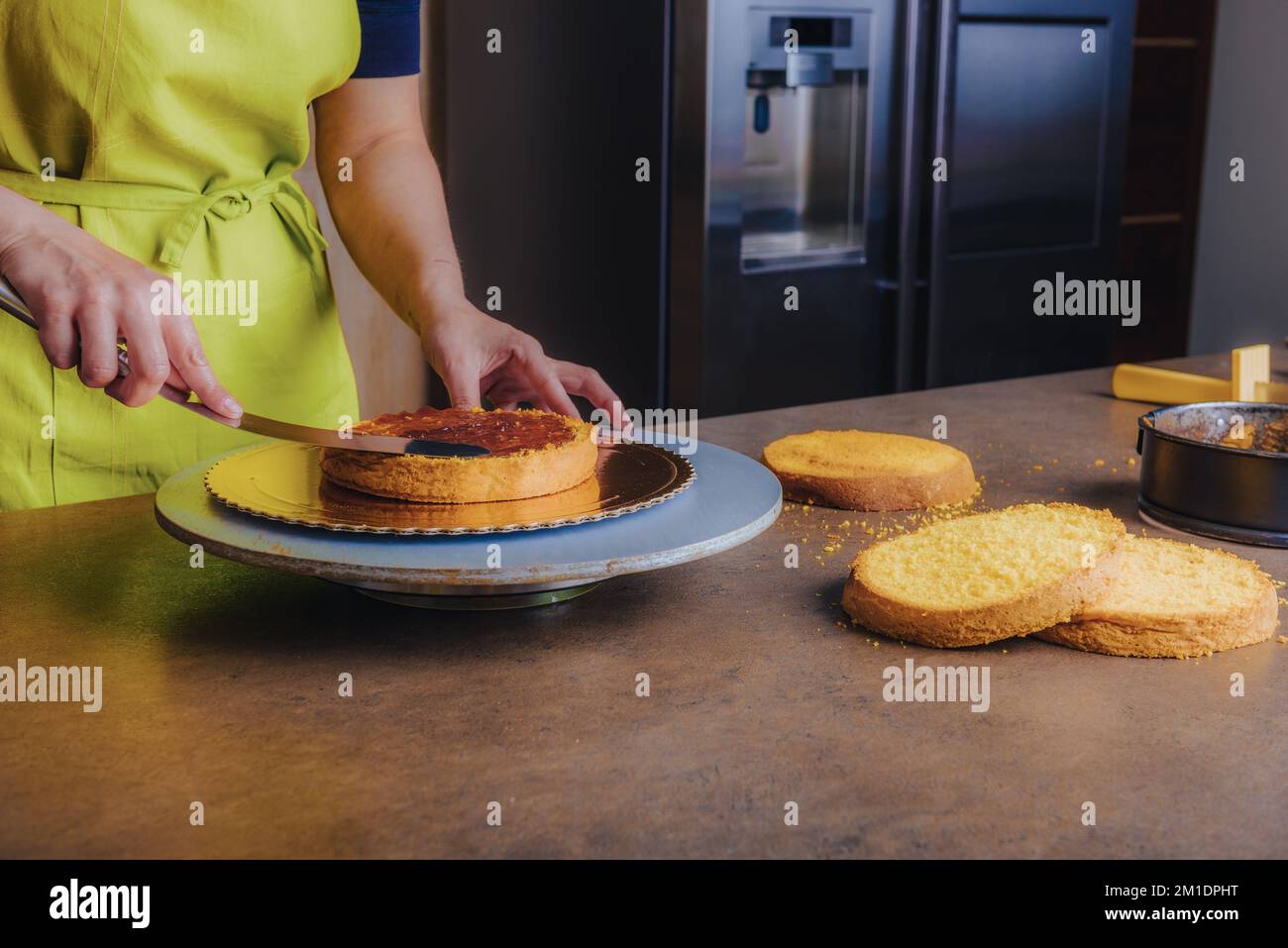 Unrecognisable woman spreding homemade jam on a delicious sponge cake ...