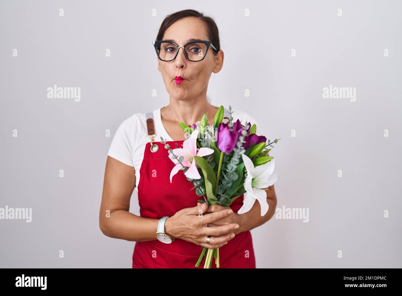 Middle age brunette woman wearing apron working at florist shop holding ...