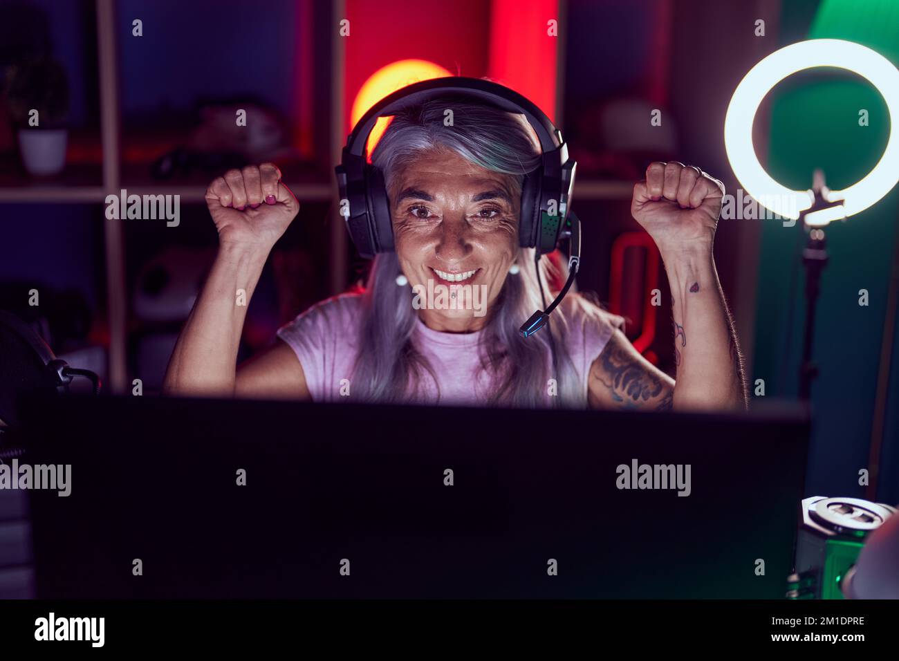 Middle age grey-haired woman streamer playing video game with winner ...