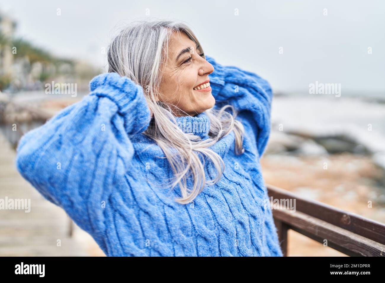 Middle age grey-haired woman smiling confident relaxed with hands on ...