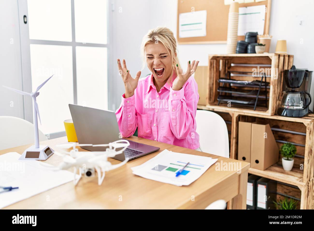 Young caucasian woman working at the office celebrating mad and crazy ...