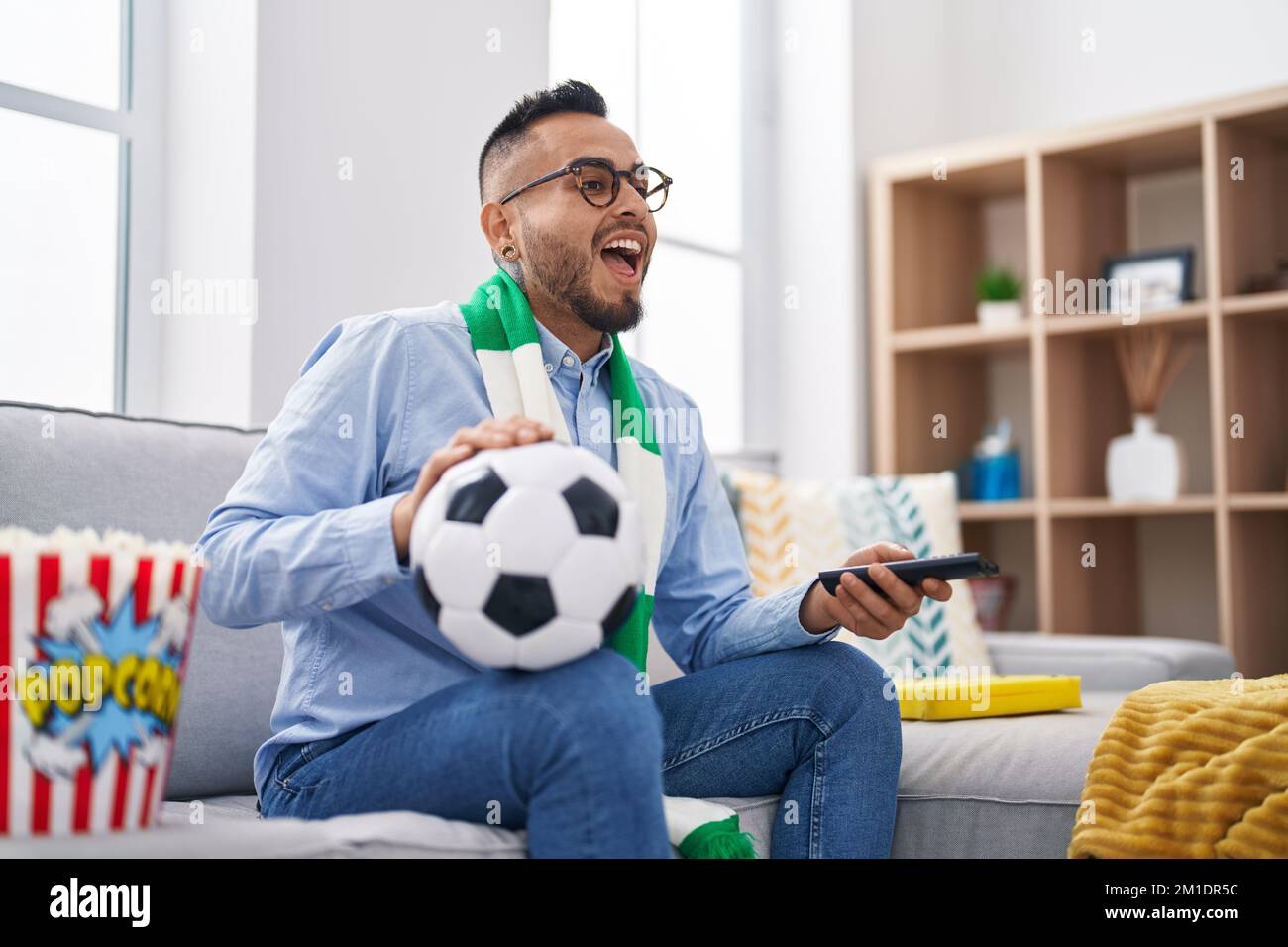 Young hispanic man football hooligan holding ball supporting team ...