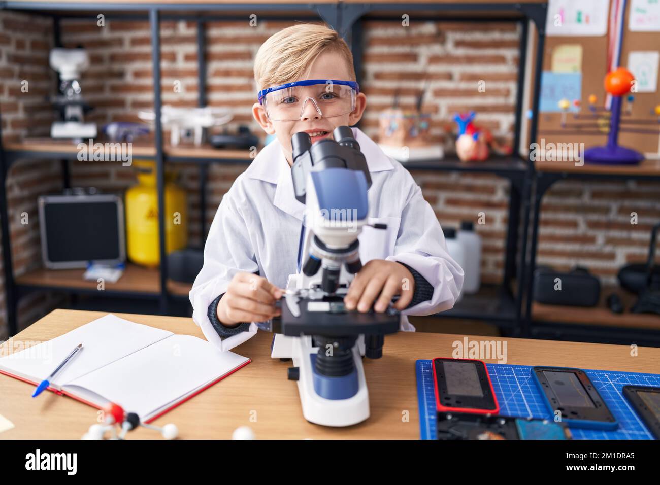 Adorable toddler student using microscope standing at classroom Stock ...