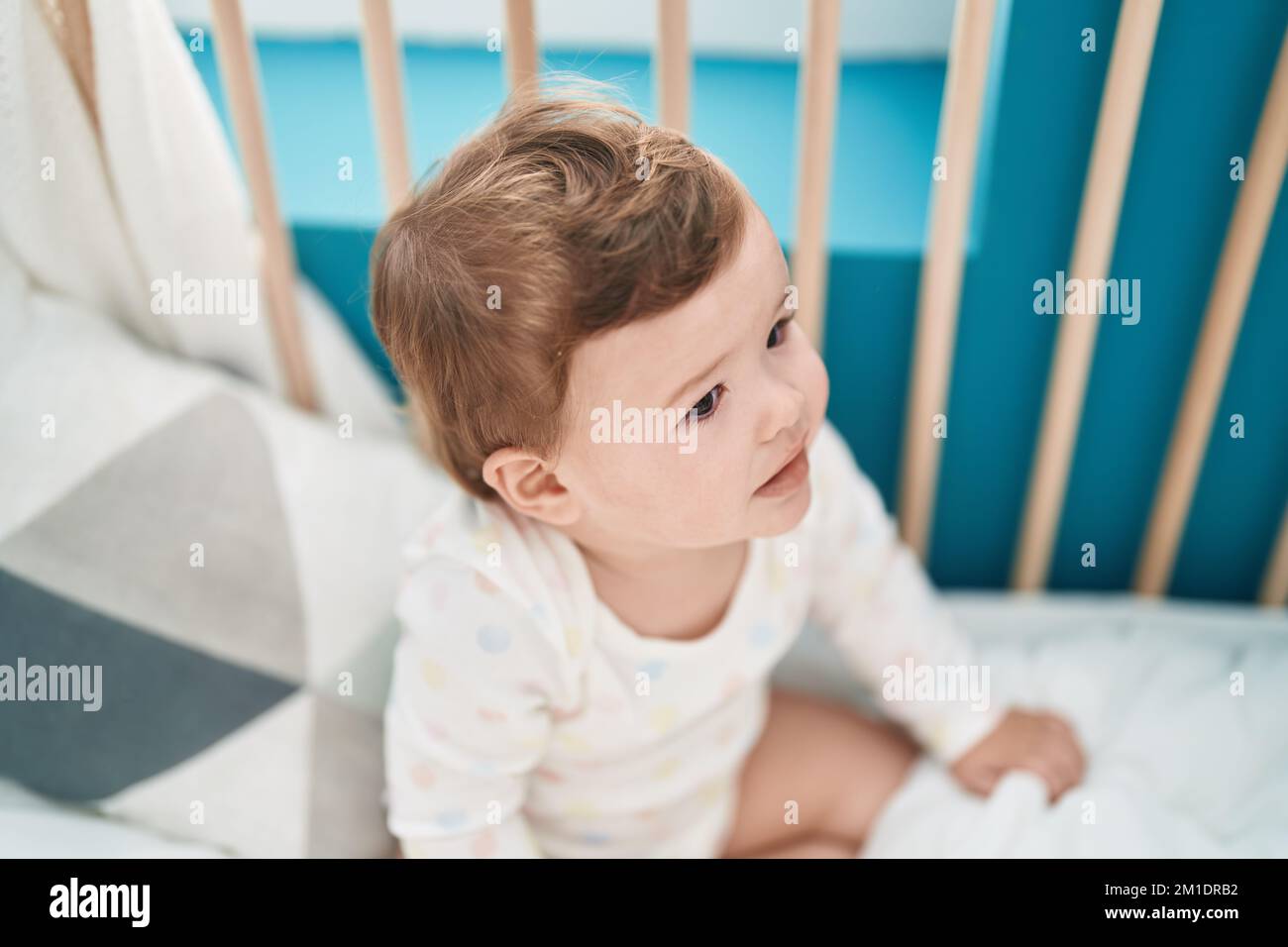 Adorable caucasian baby sitting on cradle at bedroom Stock Photo - Alamy