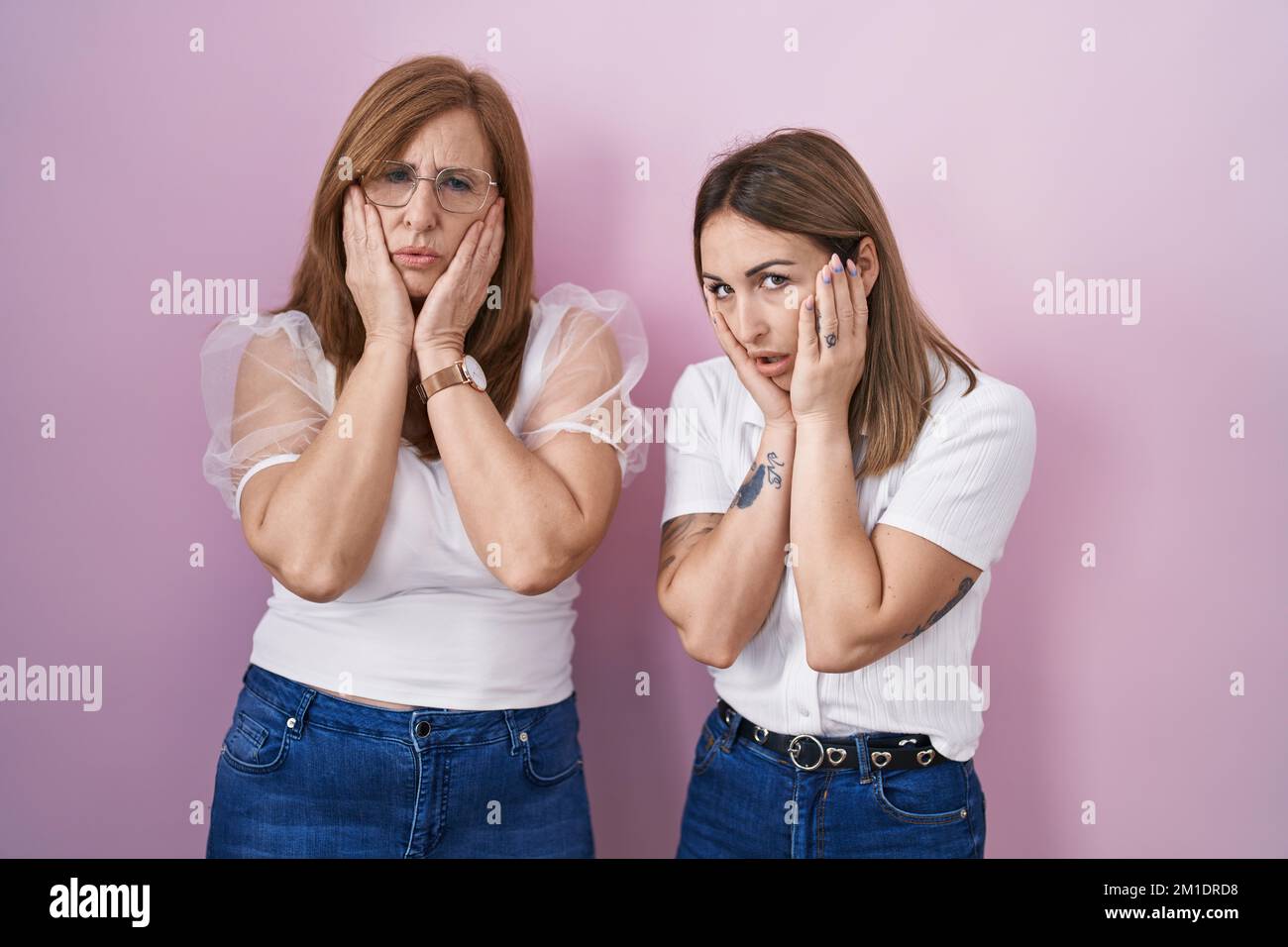 Hispanic mother and daughter wearing casual white t shirt over pink ...