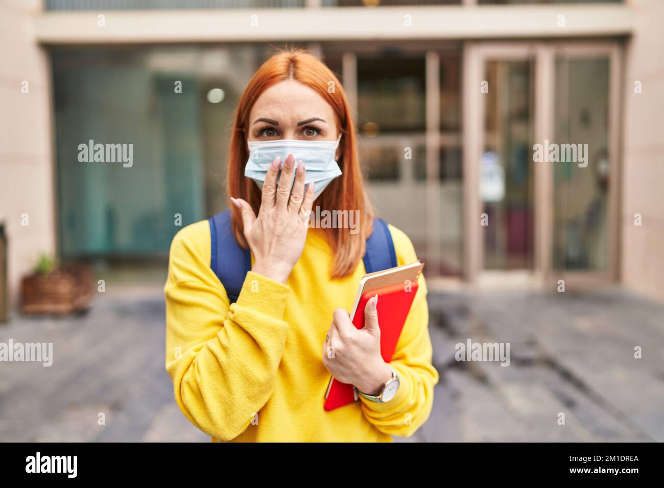 Young woman wearing safety mask and student backpack holding books ...