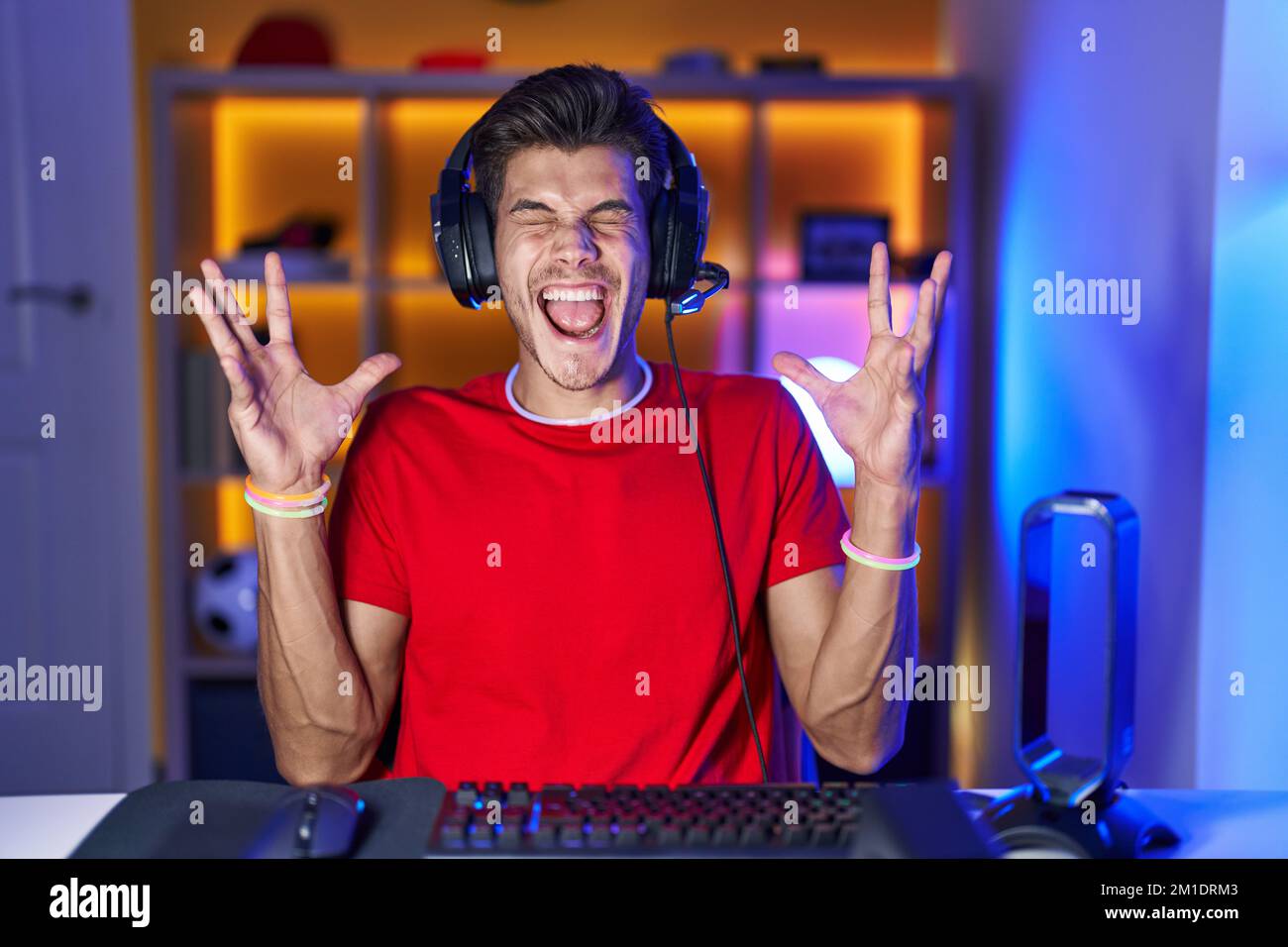 Young hispanic man playing video games celebrating mad and crazy for ...