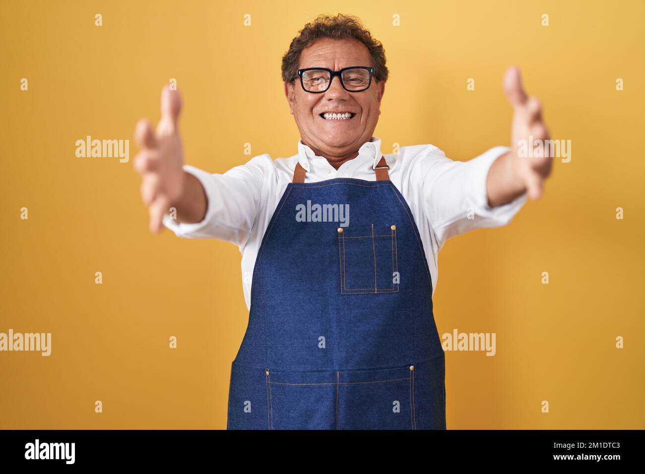 Middle age hispanic man wearing professional cook apron looking at the ...