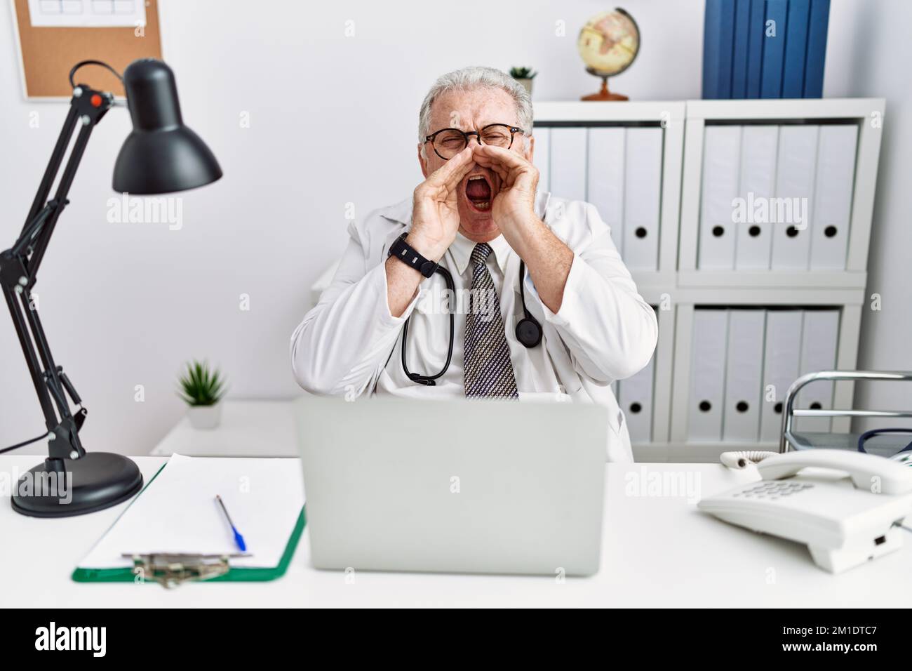 Senior caucasian man wearing doctor uniform and stethoscope at the ...