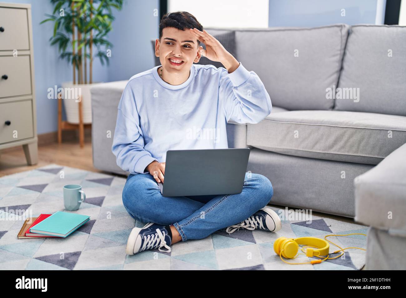 Non binary person studying using computer laptop sitting on the floor ...