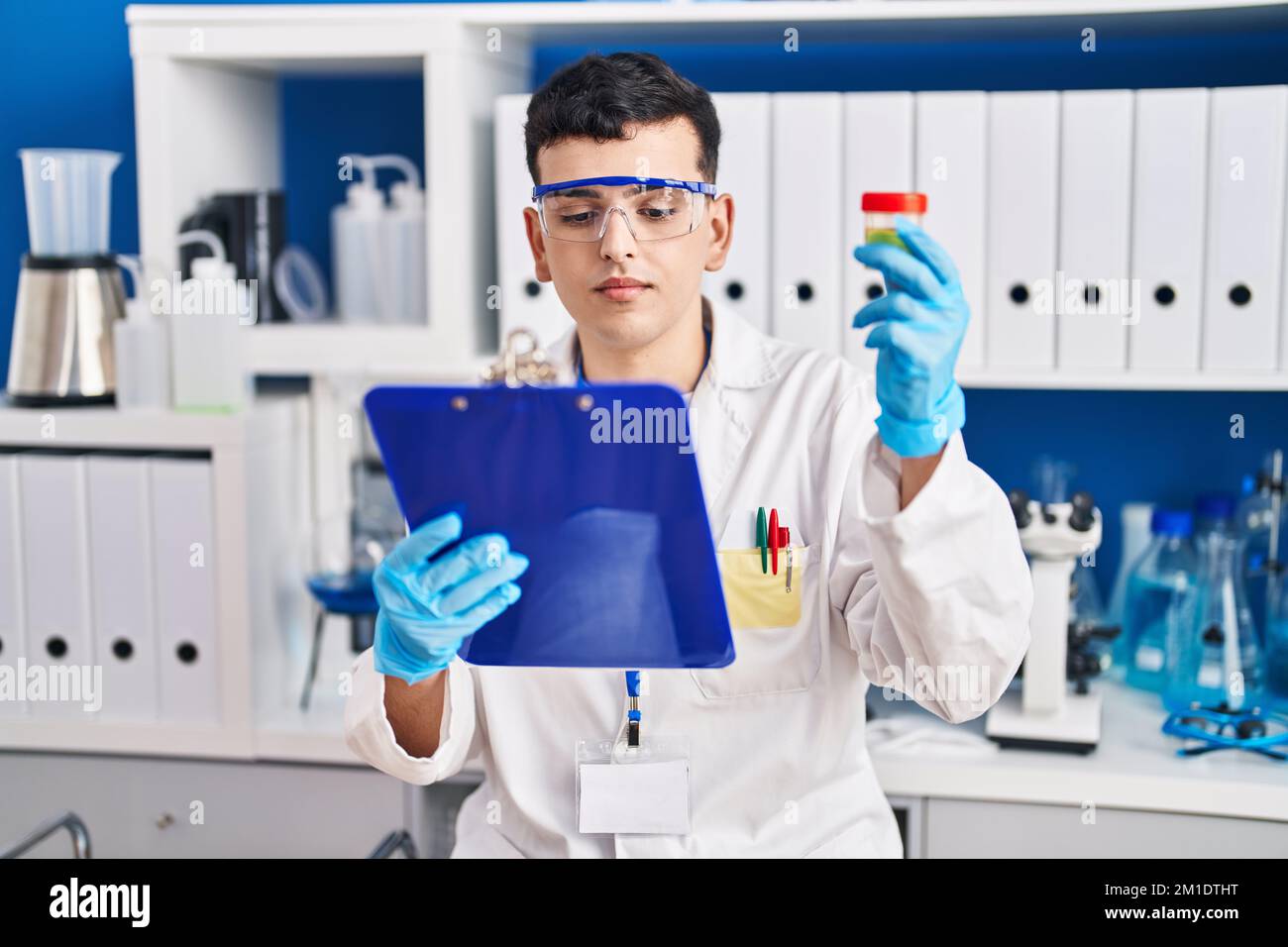 Young non binary man scientist reading report holding urine test tube ...