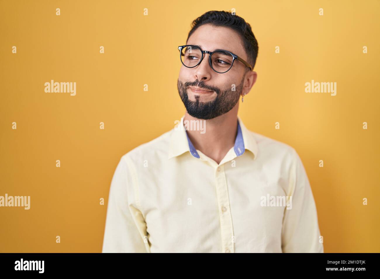 Hispanic young man wearing business clothes and glasses smiling looking ...