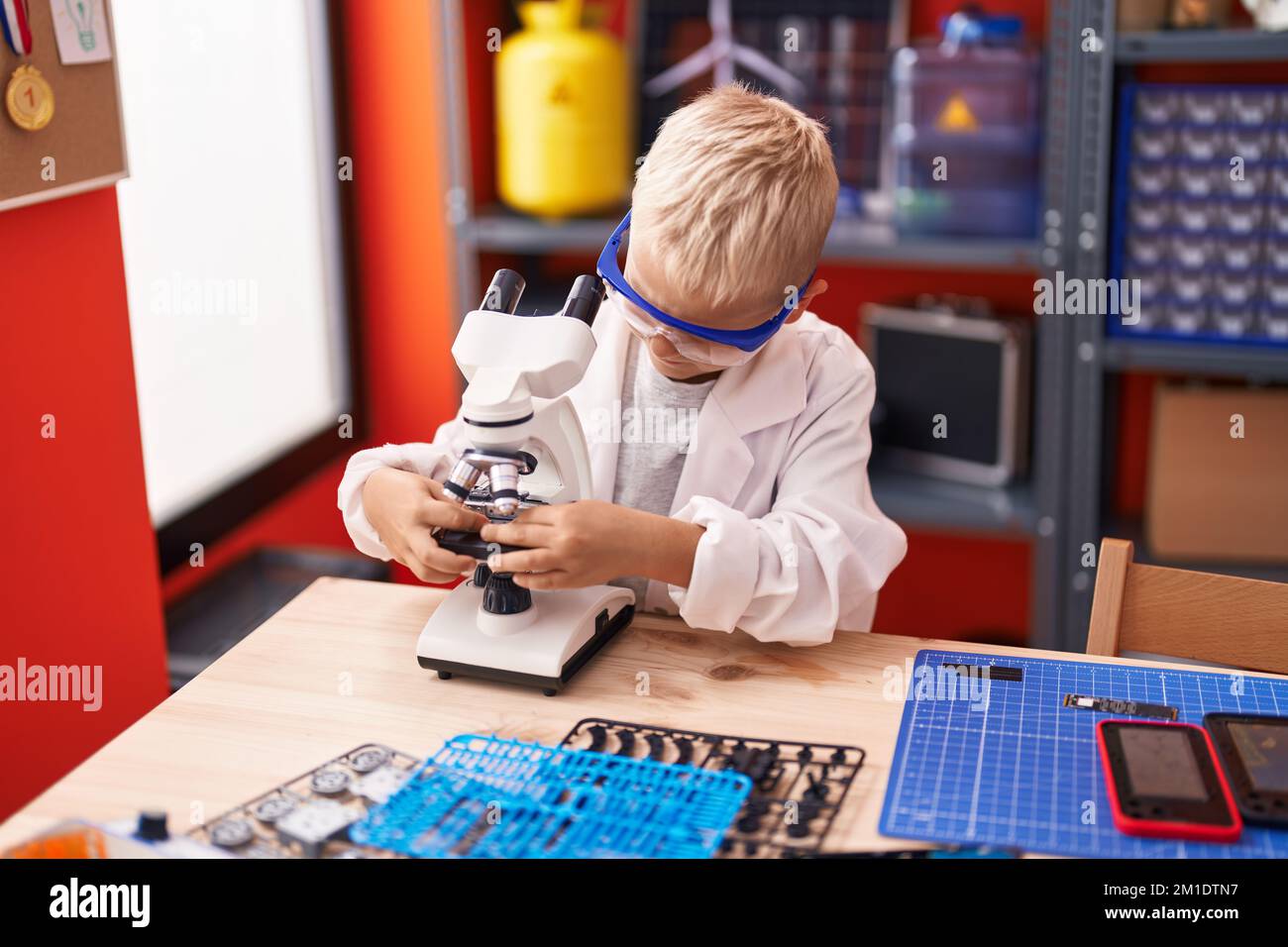 Adorable toddler student using microscope standing at classroom Stock ...