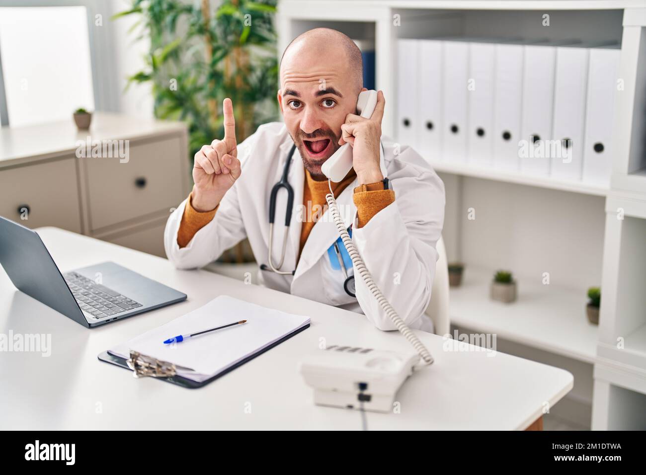 Young bald man with beard working on telephone appointment surprised ...