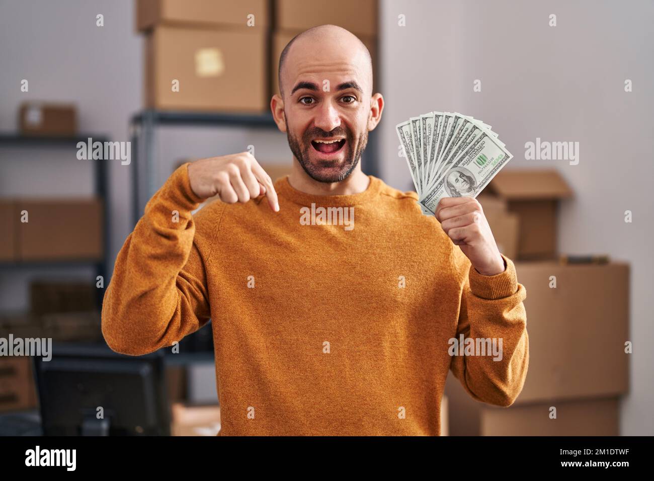 Young bald man with beard working at small business ecommerce holding ...