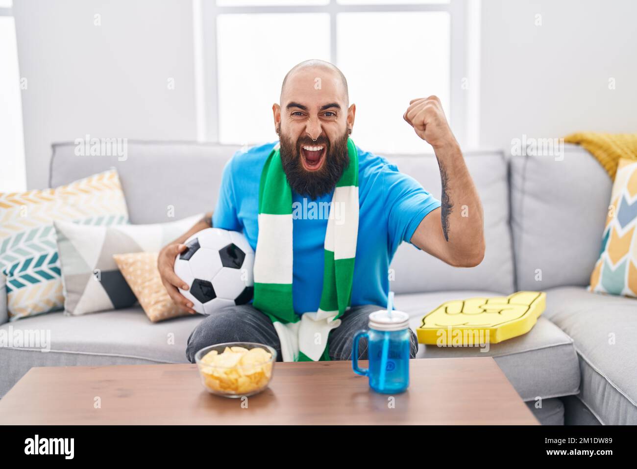 Young hispanic man with beard and tattoos football hooligan holding ...