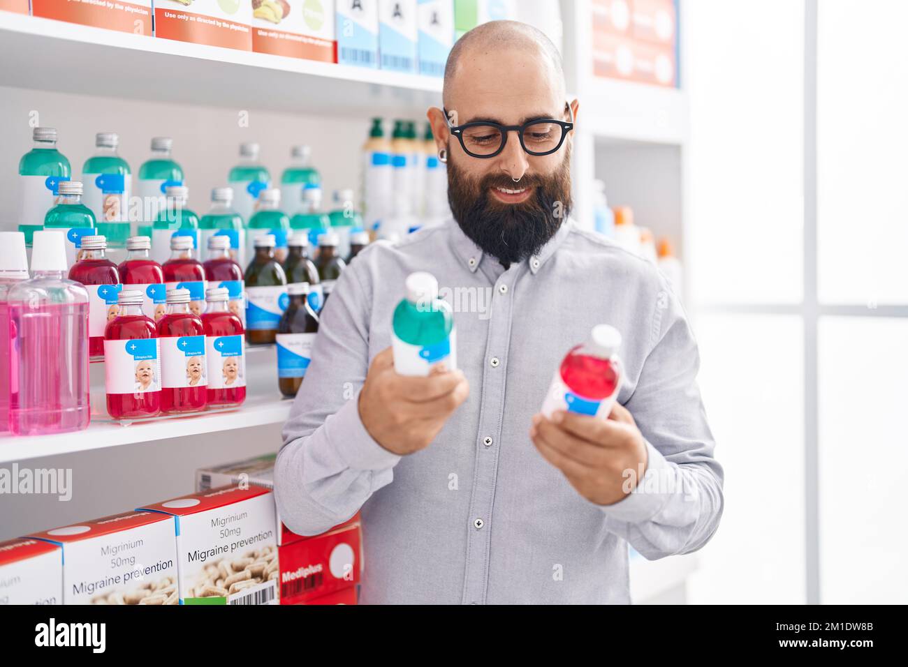 Young bald man customer smiling confident holding medication bottles at ...