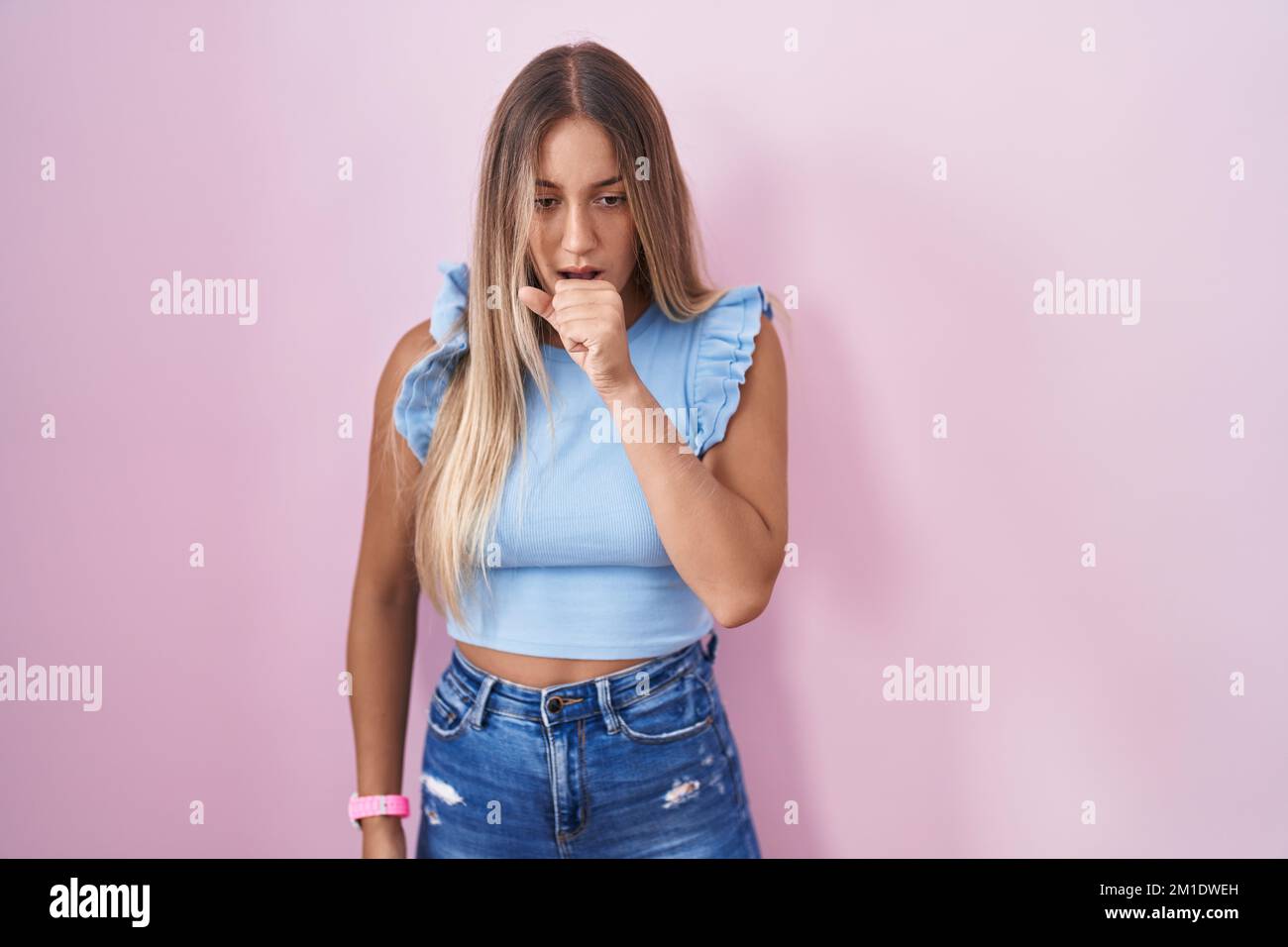 Young blonde woman standing over pink background feeling unwell and ...