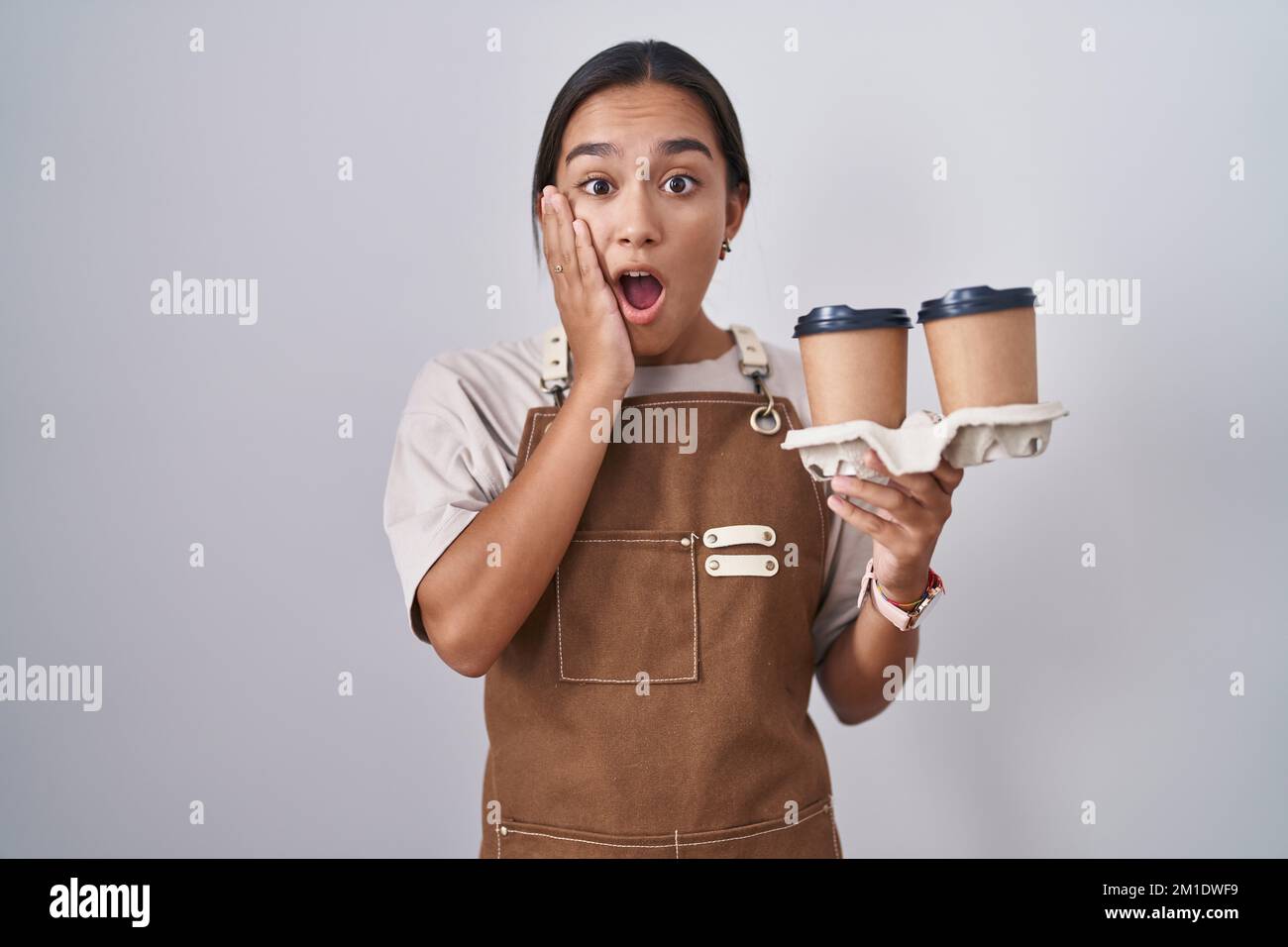 Young hispanic woman wearing professional waitress apron holding coffee ...