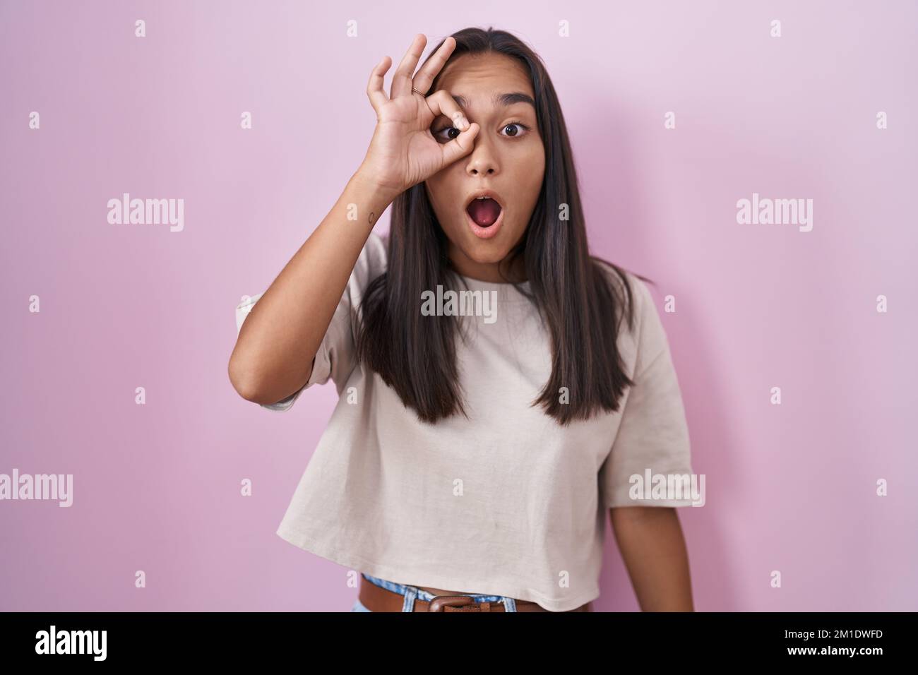Young hispanic woman standing over pink background doing ok gesture ...