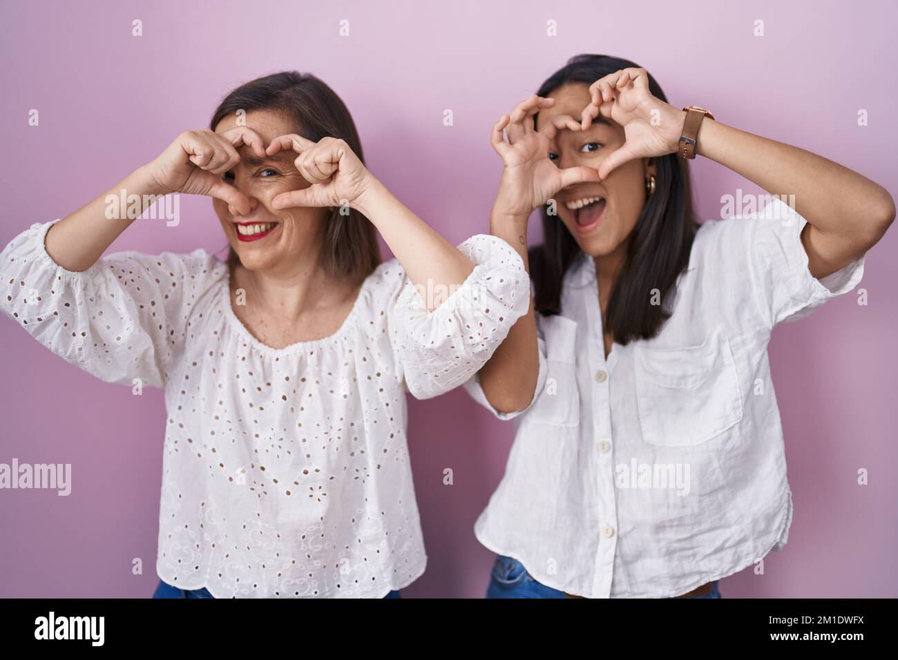 Hispanic mother and daughter together doing heart shape with hand and ...