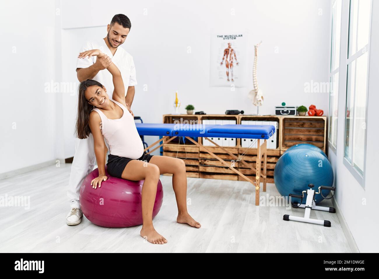 Latin man and woman wearing physiotherapist uniform having pregnancy ...