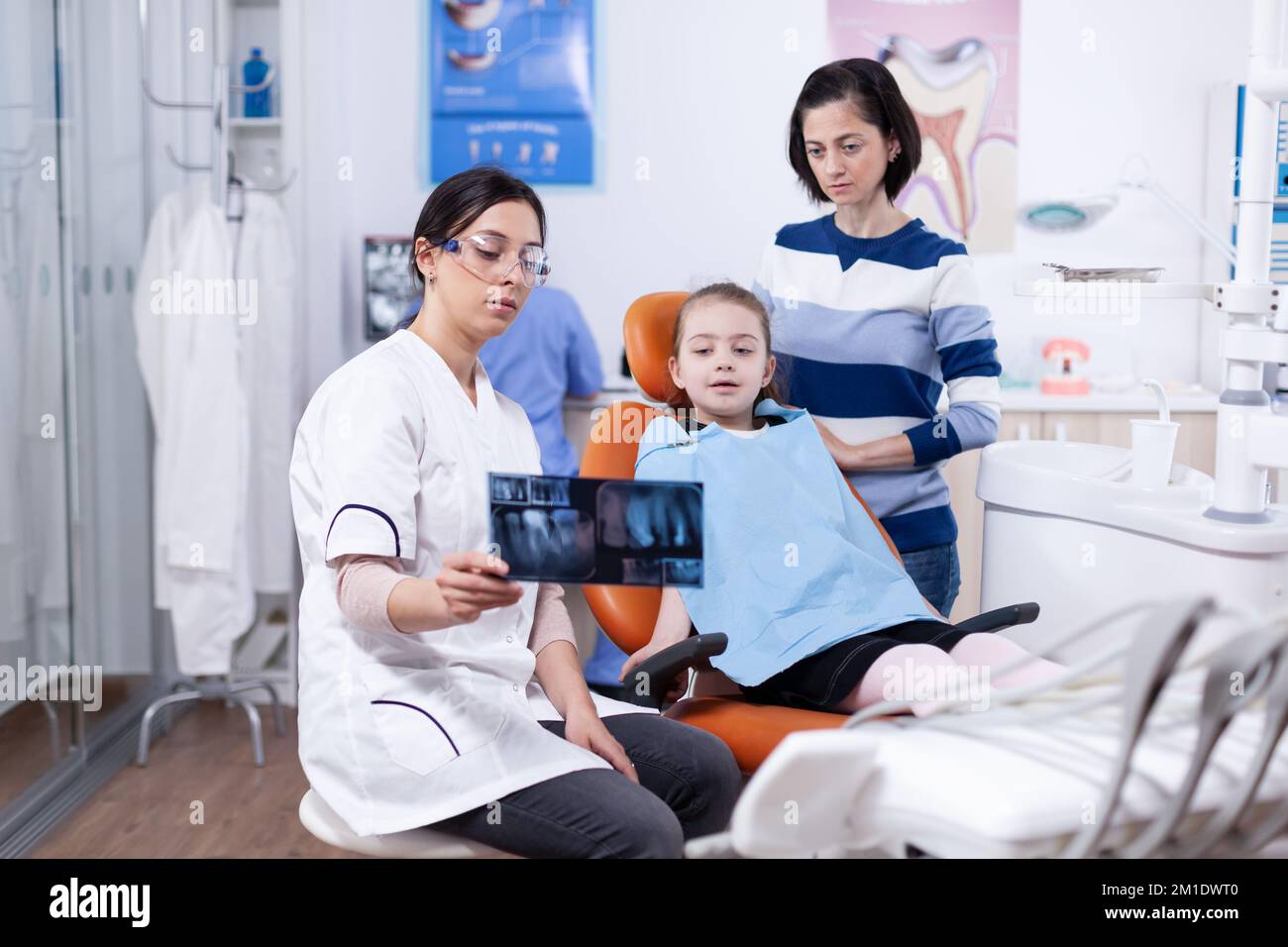 Dentistiry specialist talking about cavity procedure to kid wearint ...