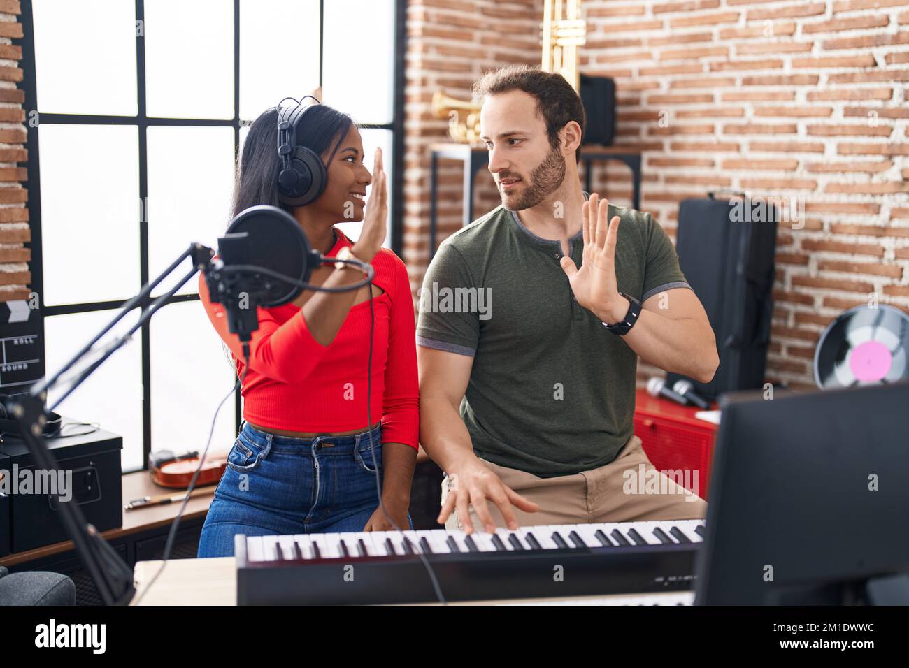 Man and woman musicians high five with hands raised up at music studio ...