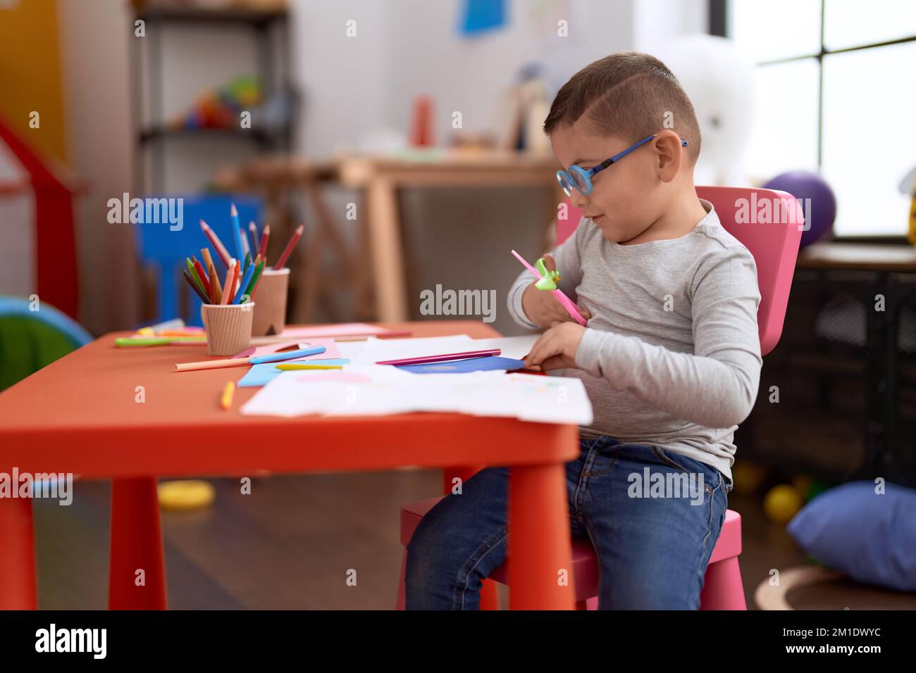 Adorable hispanic toddler student cutting paper at classroom Stock ...