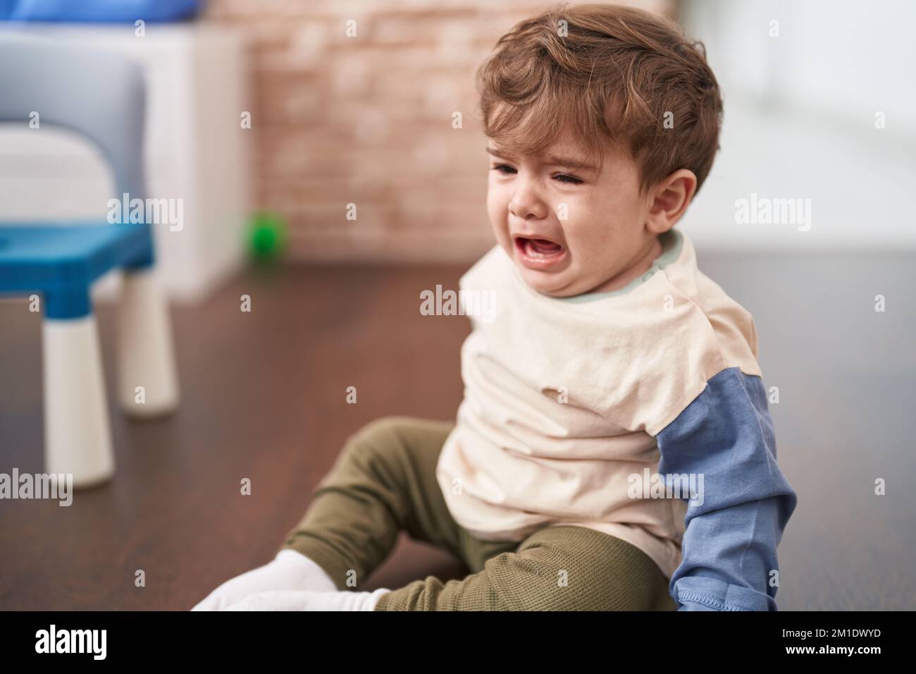 Adorable hispanic toddler sitting on floor crying at home Stock Photo ...
