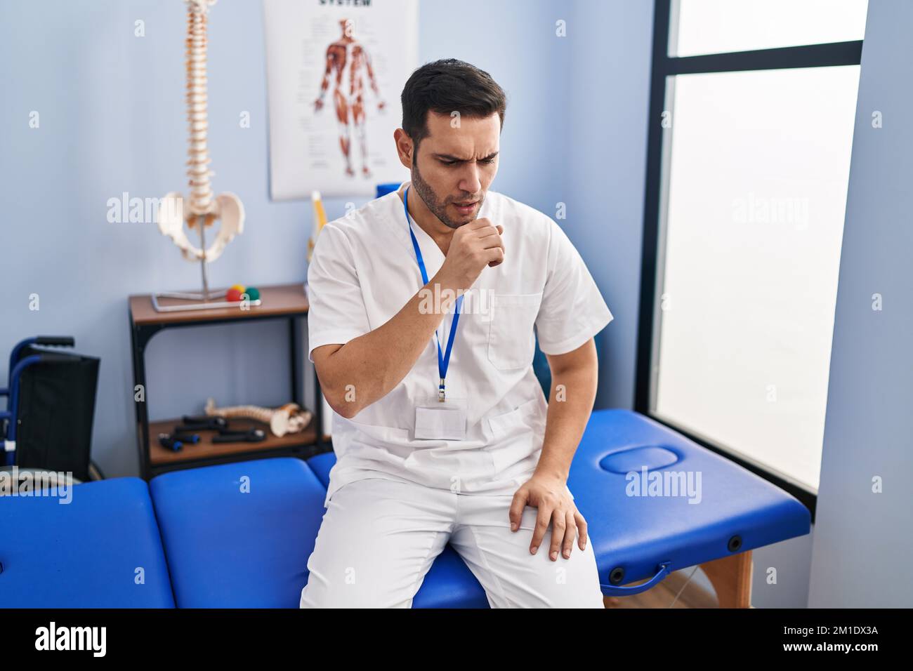 Young hispanic man with beard working at pain recovery clinic feeling ...