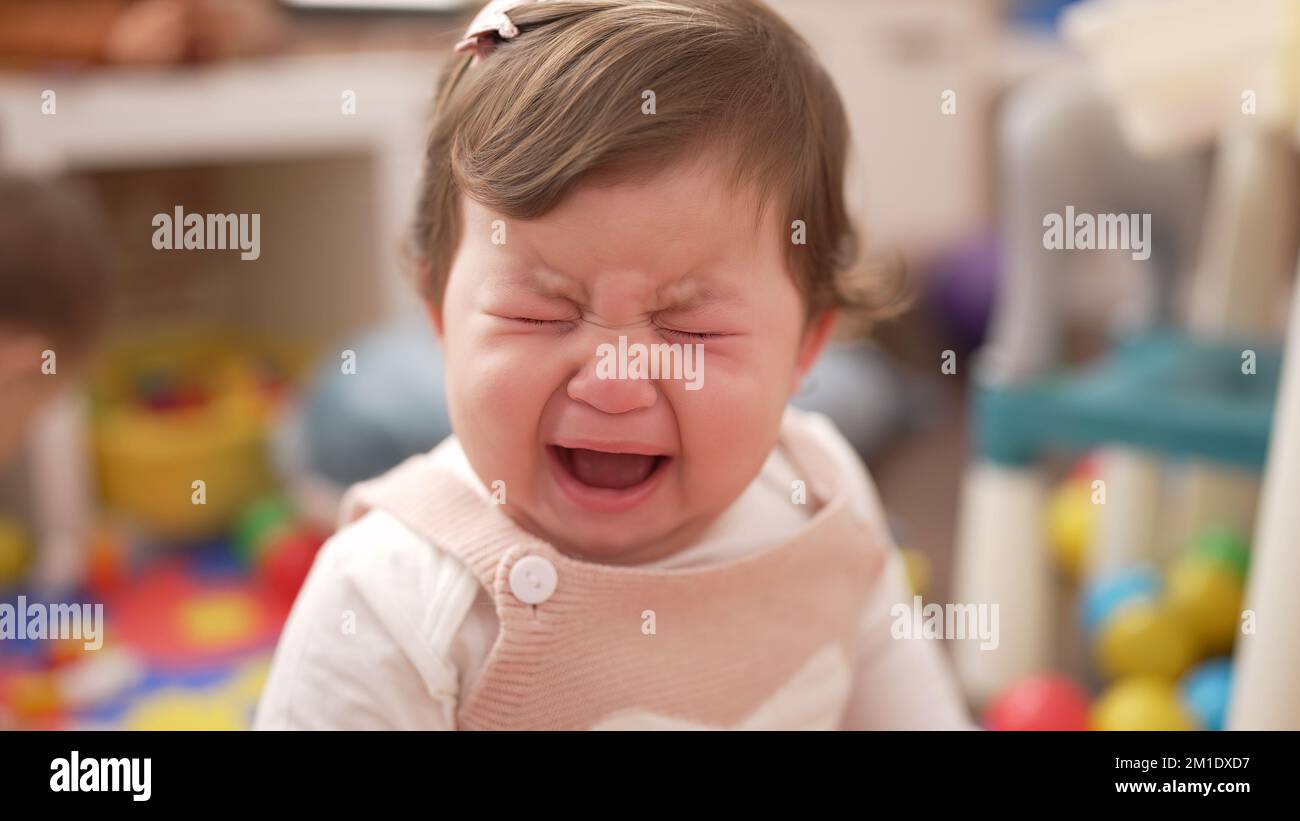 Adorable toddler sitting on floor crying at kindergarten Stock Photo ...