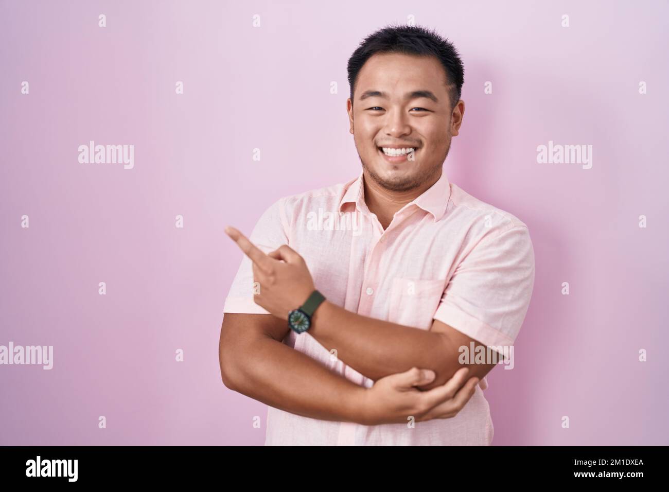 Chinese young man standing over pink background with a big smile on ...