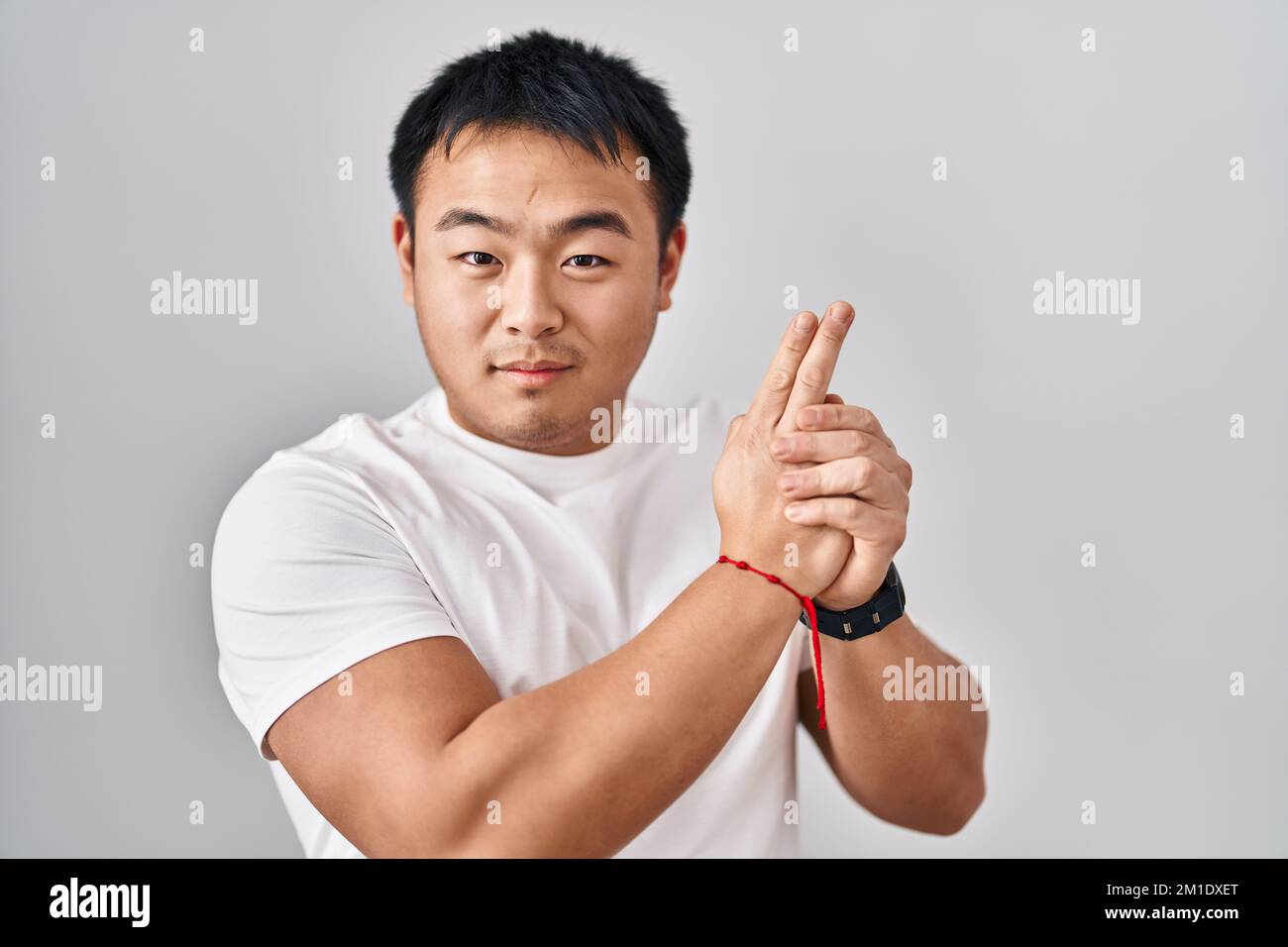 Young chinese man standing over white background holding symbolic gun ...