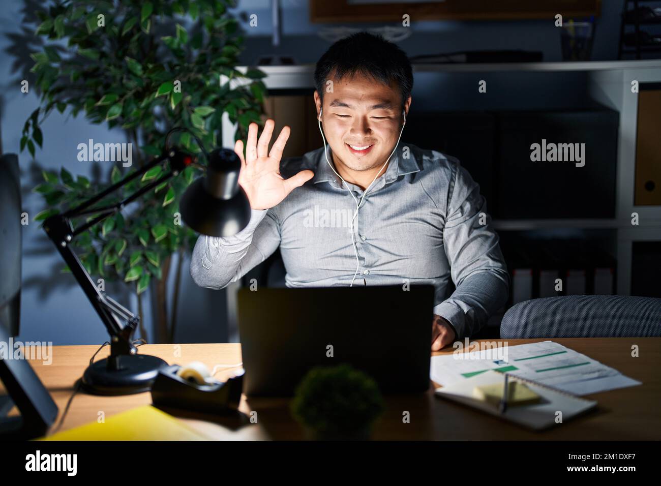 Young chinese man working using computer laptop at night showing and ...