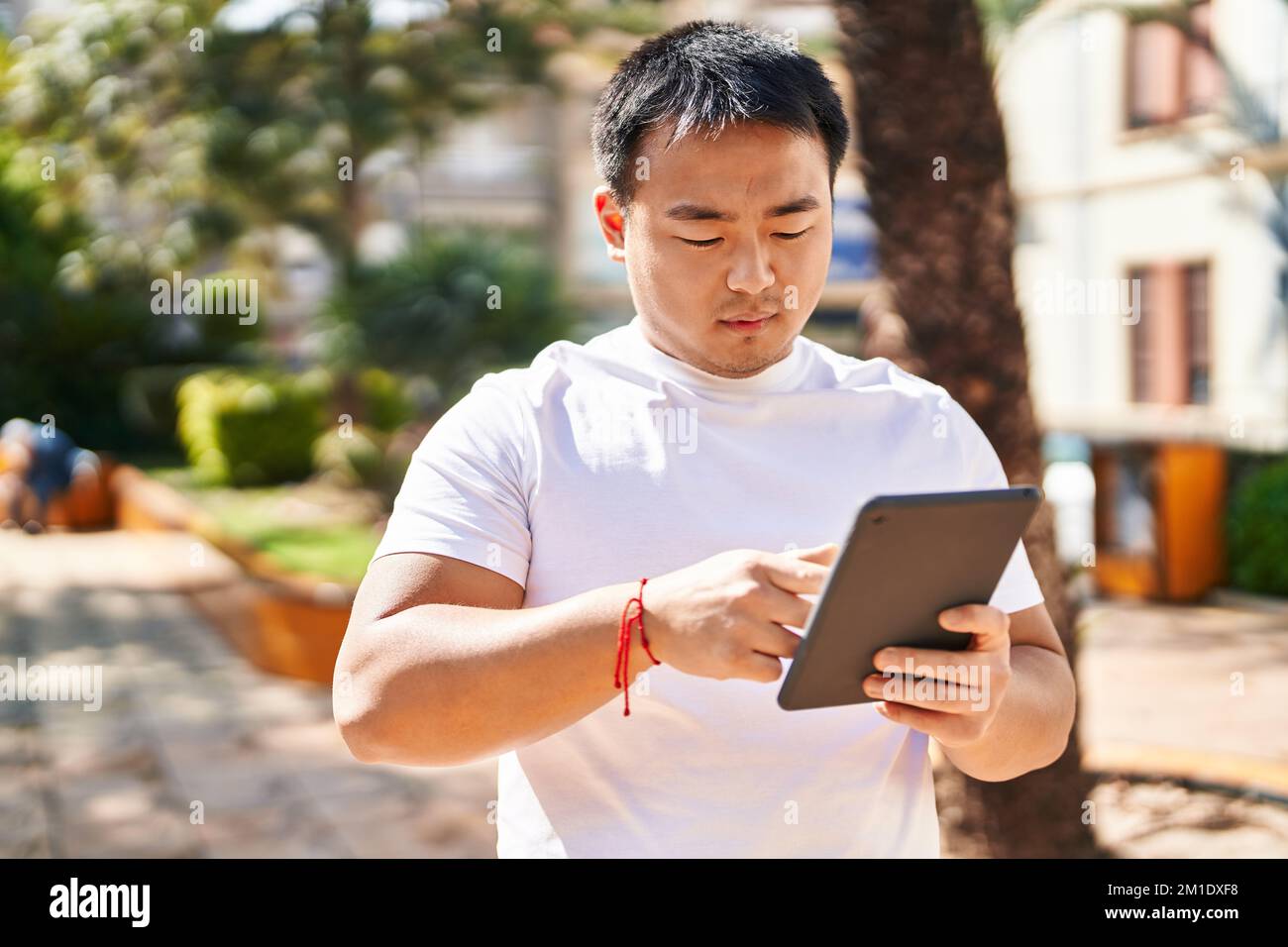 Young chinese man using touchpad at park Stock Photo - Alamy