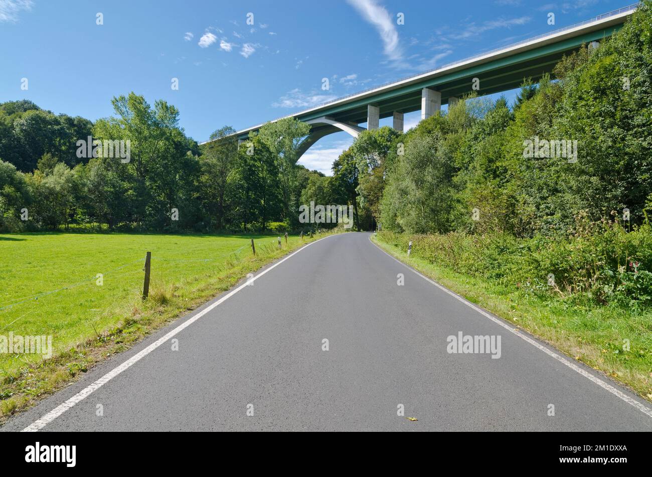 Freeway viaduct spanning across a green valley with a paved road Stock ...
