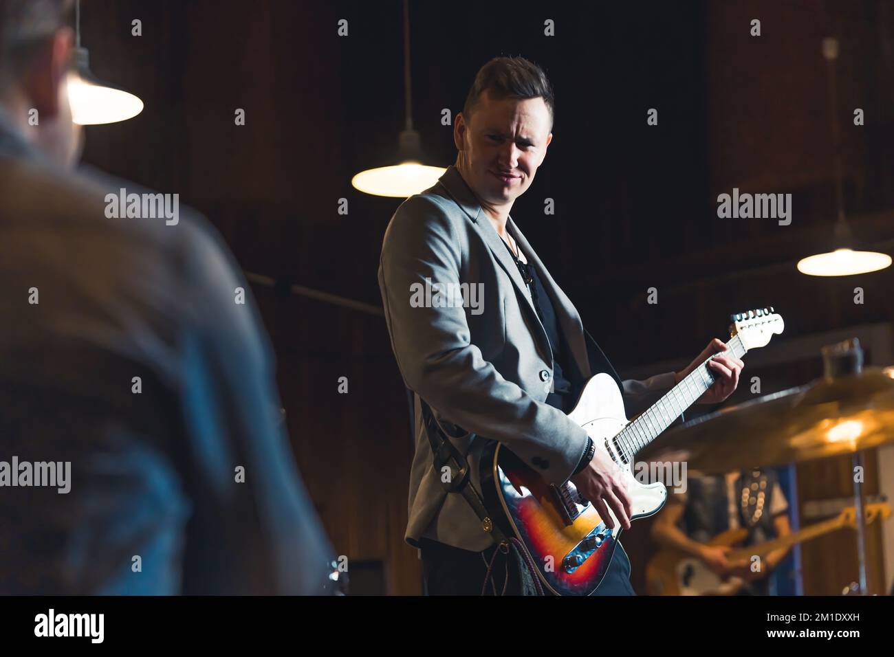 Confused male guitarist looking at band drummer. Mid adult caucasian ...