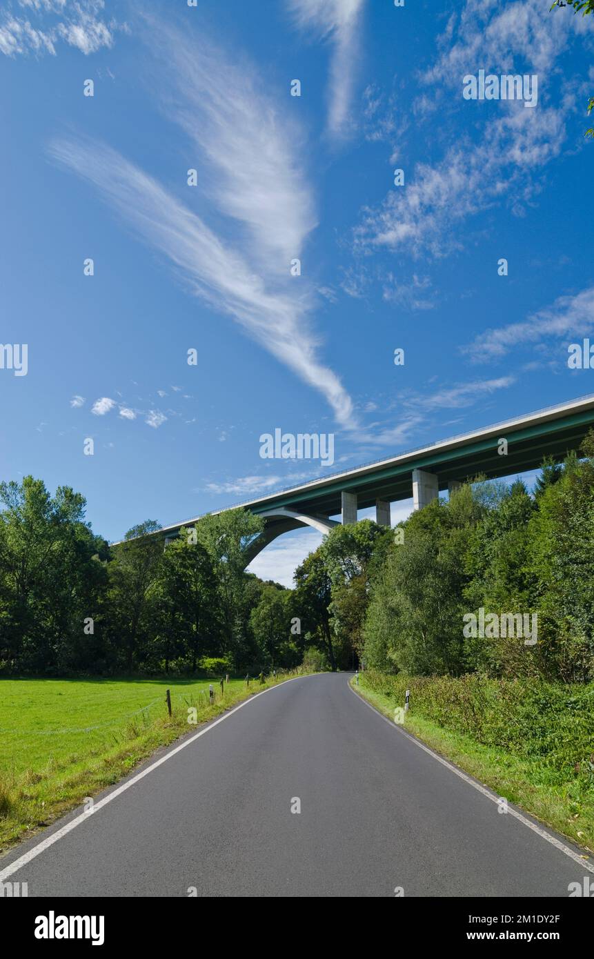 Freeway viaduct spanning across a green valley with a paved road Stock ...