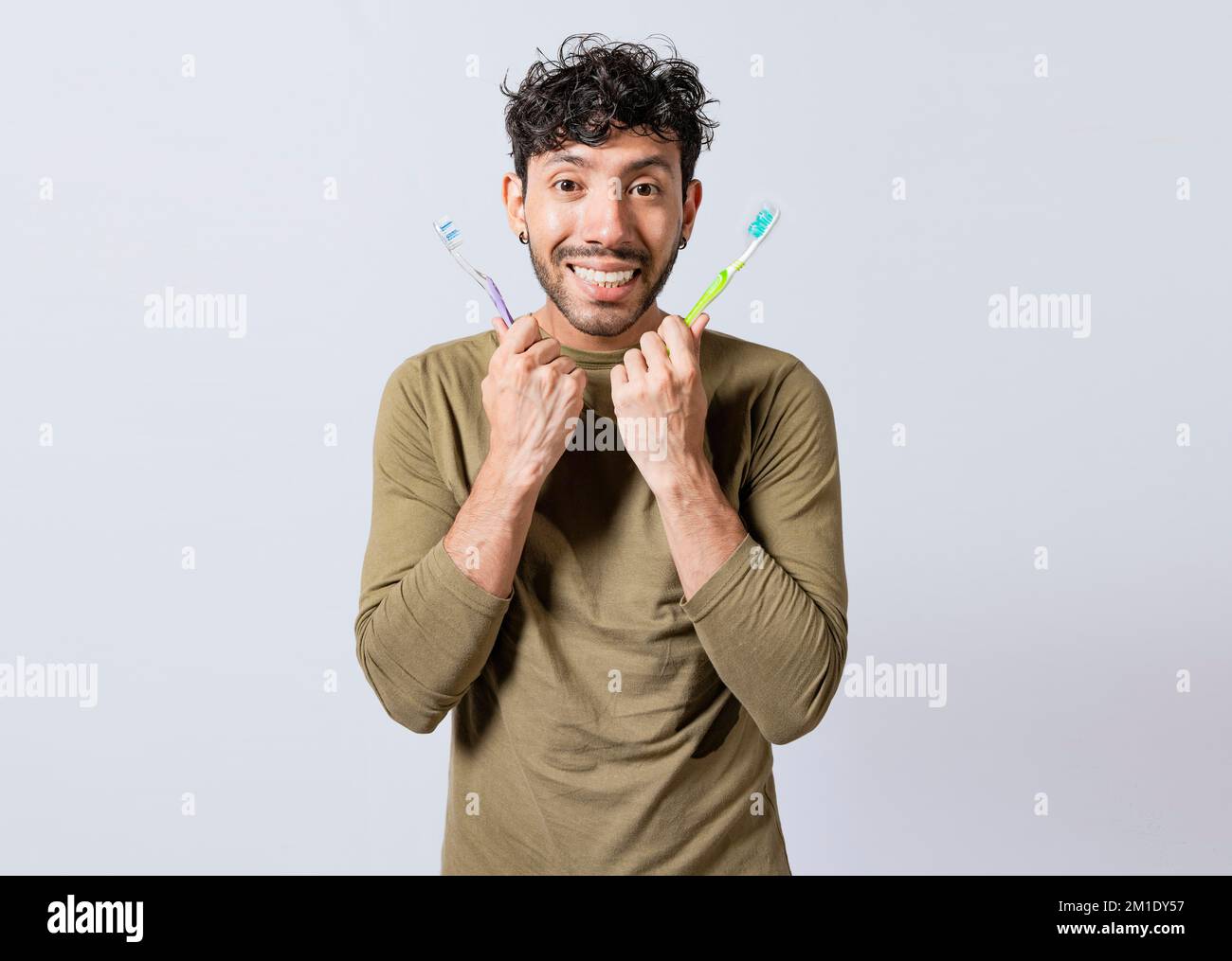 Handsome man holding two toothbrushes isolated. Smiling guy holding two ...