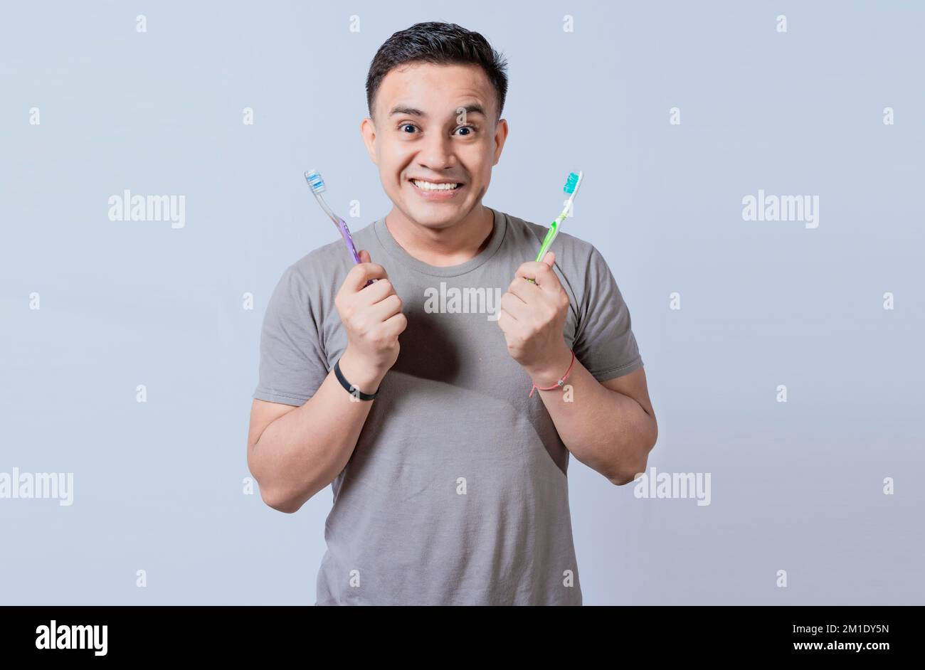 Smiling guy holding two toothbrushes isolated. Smiling people showing ...