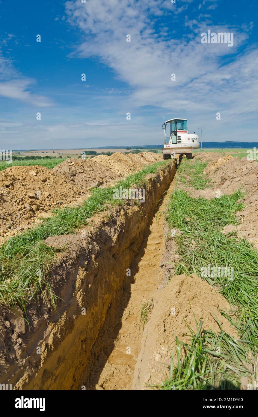Excavator digging a channel through agriculture landscape Stock Photo ...