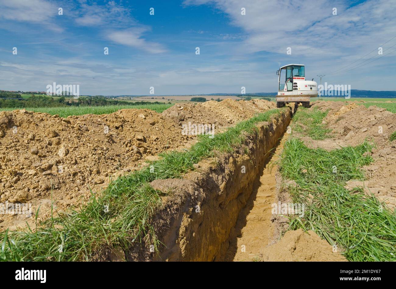 Excavator digging a channel through agriculture landscape Stock Photo ...