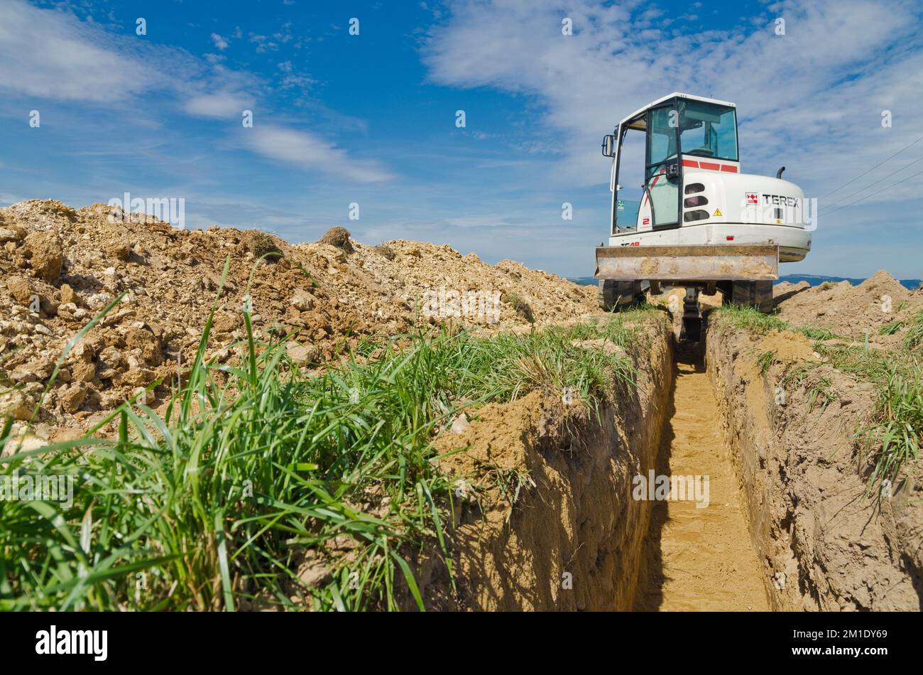 Excavator digging a channel through agriculture landscape Stock Photo ...