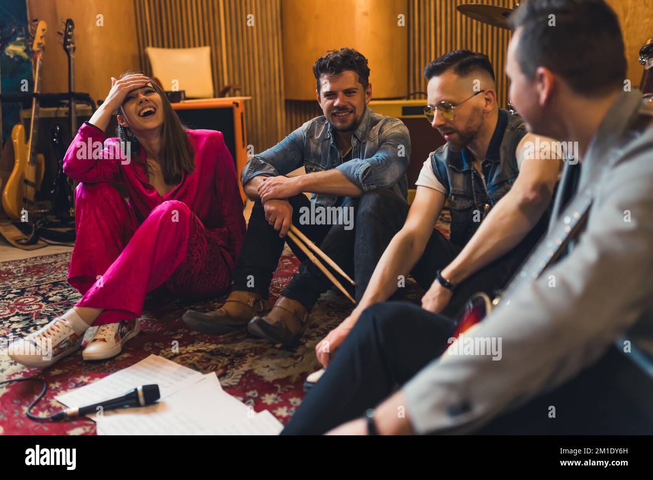 Happy band members sit on colourful carpet and write music and lyrics ...