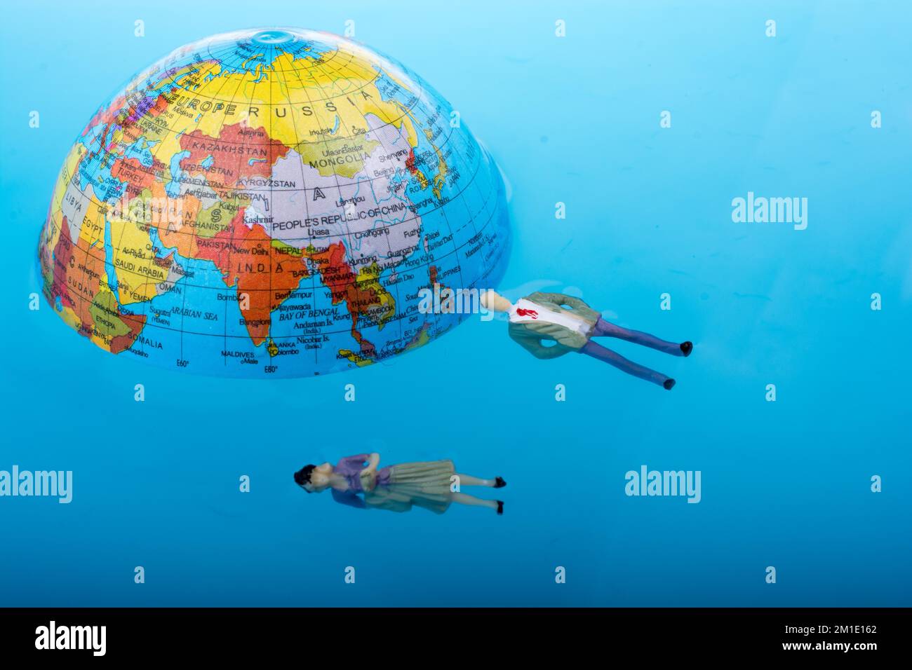 Little globe with floating figurines around in water Stock Photo - Alamy