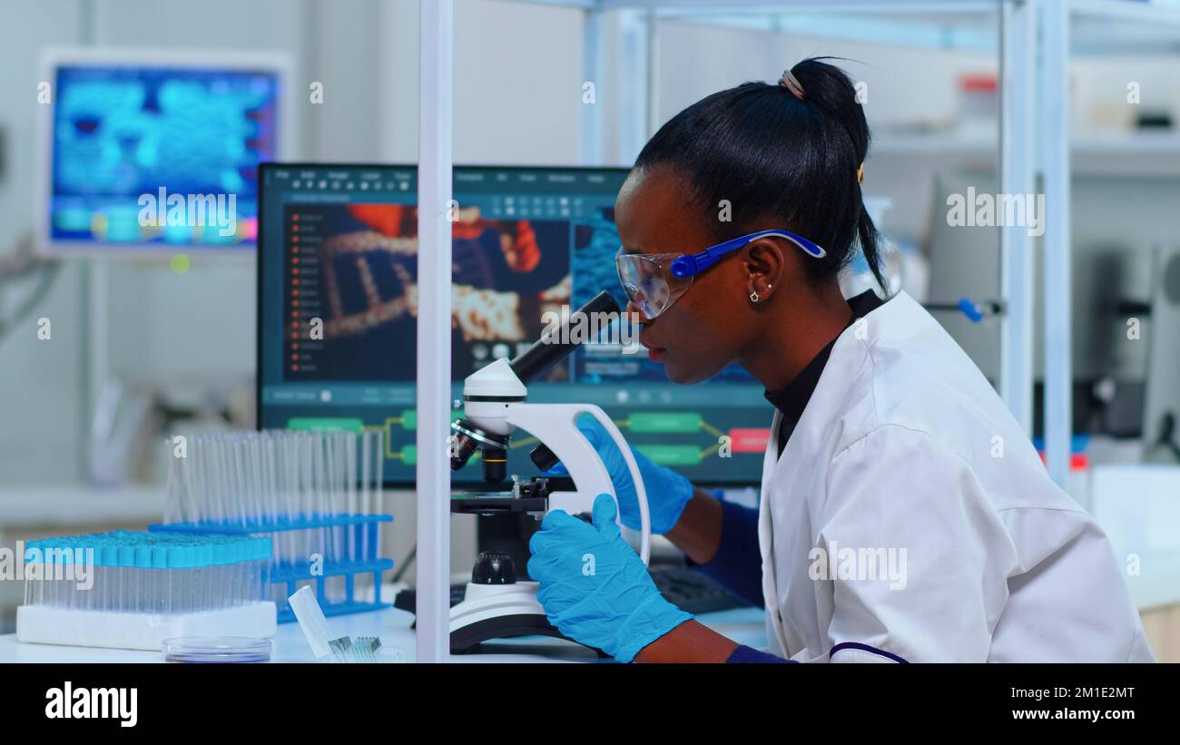 African woman biochemist using microscope in modern equipped laboratory ...
