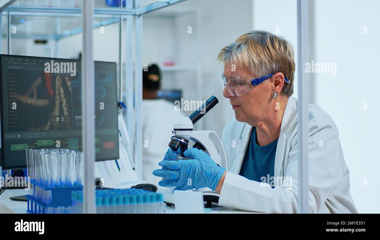 Elderly biotechnology scientist researching in modern equipped ...