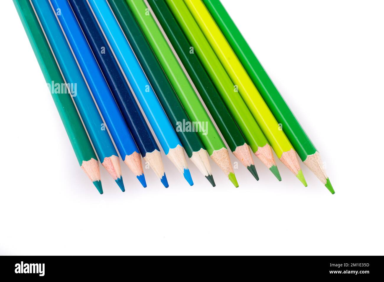 Color Pencils of various tones of green and blue color on a white ...